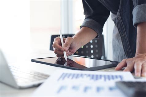 디지털 태블릿 및 노트북 컴퓨터와 재무 보고서 그래프 데이터 문서를 책상에 올려 놓고 사무실에서 일하는 사업가 비즈니스 분석 개념 클로즈 업 검색에 대한 스톡 사진 및 기타