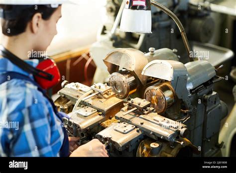 Over Shoulder View Of Busy Female Engineer Adjusting Lathe Machine For Designing Details At