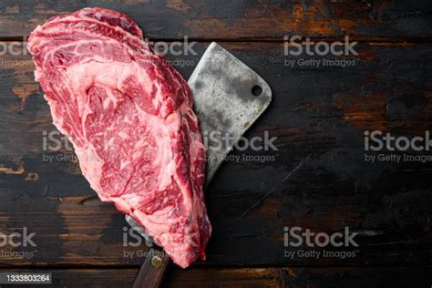 유기농 대리석 쇠고기 고기 스테이크와 조미료 리브 아이 컷 오래된 정육점 칼 오래된 어두운 나무 테이블 배경에 상단 보기 플랫