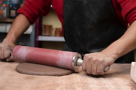 작업장에서 물건을 만들기 위해 점토 덩어리를 평평하게 하는 롤링 핀을 사용하는 도공 굴리기에 대한 스톡 사진 및 기타 이미지