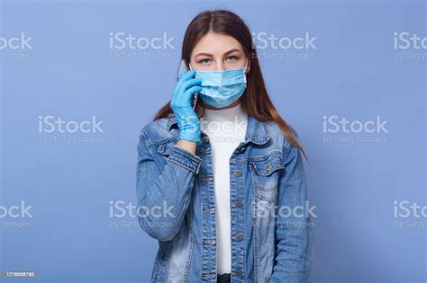 스튜디오에서 파란색 배경 위에 고립 된 긴 머리의 평화로운 아름다운 젊은 여성의 그림 검역 중에 전화를 통해 이야기 귀에 가까운