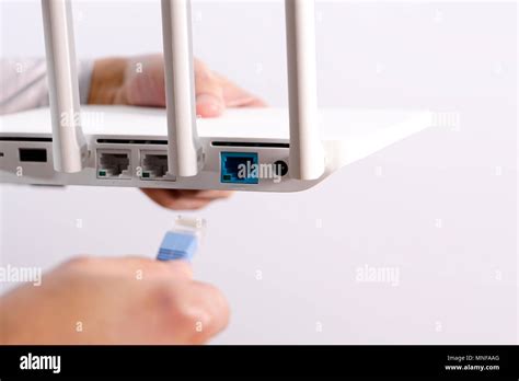 The Back View Of Router Showing The Lan Internet Port And The Hand Is Pluging In The Land Cable