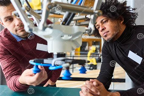 Engineers Examining Robotic Gripper Arm During Industrial Automation Training Session Stock