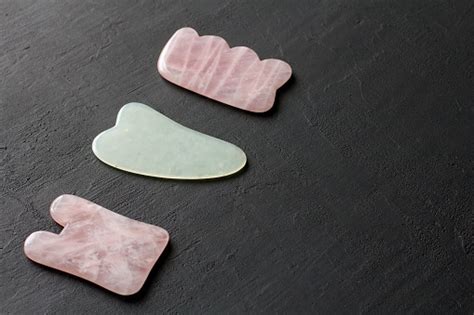 얼굴 몸 마사지 도구 천연 석 미네랄 로즈 쿼 츠 흰색 옥 검은 배경에 거짓말 돌 치료 구아차의 스크레이퍼와 중국 전통 마사지 텍스트의 공간 복사 개념에 대한 스톡 사진 및