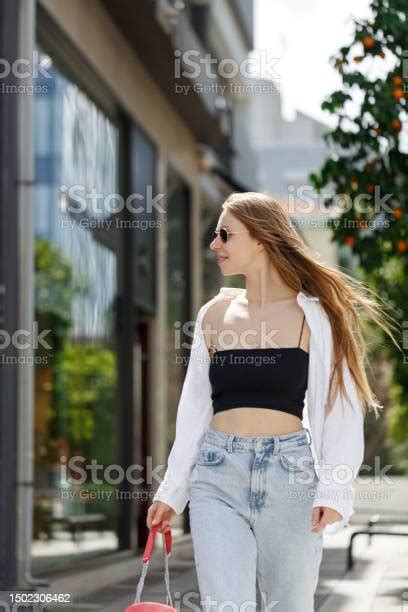 젊고 쾌활한 여성의 라이프스타일 초상화는 핸드백을 들고 야외에 서 있다 도시 여행 여름 키프로스 거리입니다 갈색 머리에 대한