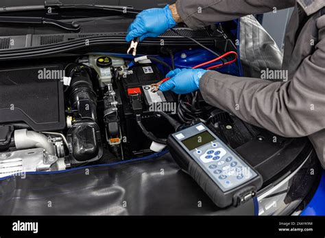 Car Master Mechanic Checking And Testing Automotive Battery With Digital Electronic Battery