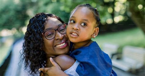 매력적인 젊은 아프리카 어머니의 초상화는 어린 딸을 안고 도시 공원에서 함께 산책하는 시간을 즐기고 있습니다 공원에서 파란 드레스를 입은 행복한 엄마와 아이 사진