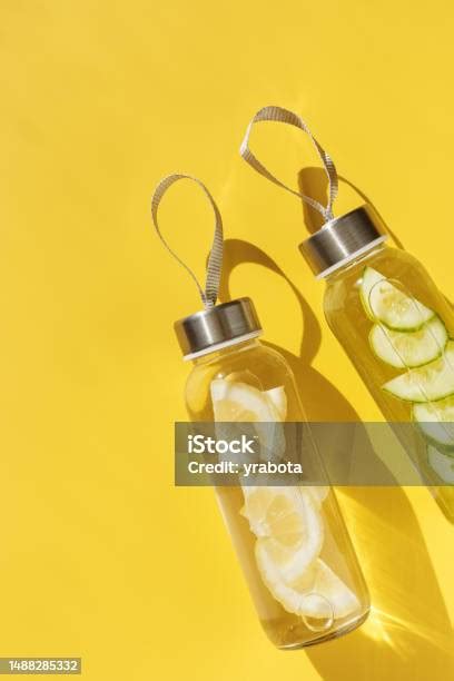 두 개의 유리병 노란색 배경에 햇빛을 쬐며 레몬과 오이가 들어간 물 음료 해독 복사 공간 주입된 물은 신진대사와 체중 감소를 촉진합니다 상쾌한 여름 음료 건강한 식생활에