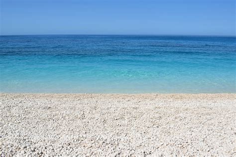 푸른 바다를 배경으로 한 모래 해변 사진 Unsplash의 무료 바닷가 이미지