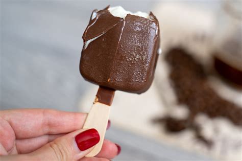 흐린 배경 매니큐어를 가진 여자 손은 반쯤 먹은 아이스크림을 들고 유리 컵에 담긴 강한 블랙 커피 에스프레소 테이블 위에 놓인