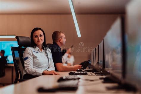 Group Of Security Data Center Operators Working In A Cctv Monitoring Room Looking On Multiple