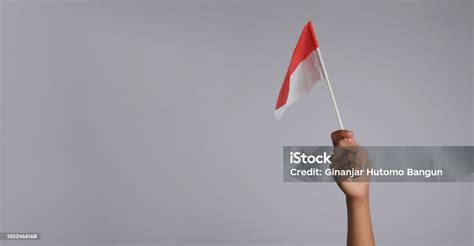 인도네시아 국기의 상징으로 빨간색과 흰색 깃발을 흔드는 손을 닫고 회색 배경에 격리된 공간을 복사합니다 8월 17일 인도네시아 독립기념일 개념 10월에 대한 스톡 사진 및