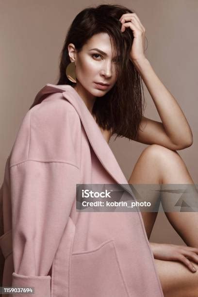 스튜디오에서 포즈를 취하는 트렌디 한 디자이너 코트의 고전적인 메이크업과 헤어 스타일을 가진 아름다운 소녀 뷰티 페이스 개인