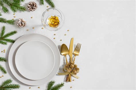 빈 접시 금 칼 붙이 와인 잔 및 흰색 배경에 전나무 가지를 제공하는 크리스마스 아름 다운 새해 테이블 설정 공간을 복사합니다