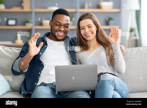 Happy Young Interracial Couple Making Video Call On Laptop At Home