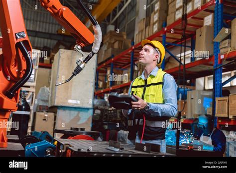 Worker Man Working With Robot Arm Automate Welding Machine In Modern Metal Factory Engineer