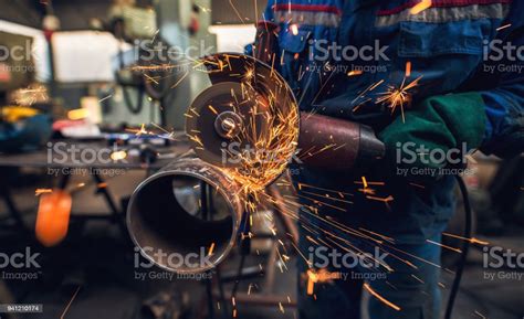 유니폼에서 전문 근 면 한 남자의 볼을 측면 가까이 스파크 산업 직물의 워크샵 이나 차고에서 비행 하는 동안 큰 전기 그 라인 더와 금속 파이프 조각을 잘라냅니다 각도에