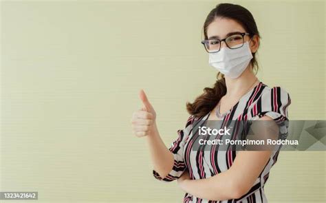 얼굴 가면을 쓰고 포즈를 취하고 엄지 손가락을 들고 어깨에 플라스틱 붕대를 가진 바이러스를 예방하고 노란 배경에 공간을 복사하는 것을 예방 접종하고 있는 인물 백인 젊은