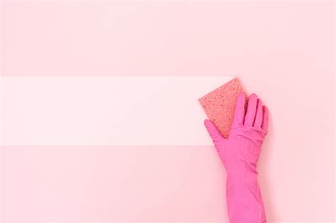 고무 장갑 파스텔 핑크 배경 텍스트에 대 한 빈 공간에 고립 된 그녀의 손에 부드럽고 작은 스폰지를 들고 있는 여자 가사