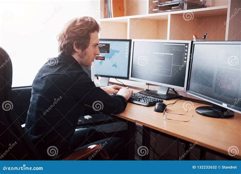 Male Programmer Working On Desktop Computer With Many Monitors At