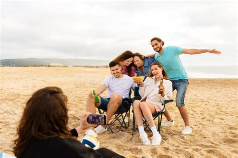 Friends Enjoying A Beach Gathering While Taking Pictures On A Summer