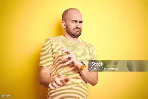 노란색 고립 된 배경 혐오 표정 위에 캐주얼 스트라이프 티셔츠를 입고 수염을 가진 젊은 대머리 남자 혐오 스러운 반응 때문에 혐오 얼굴을 하 고 불쾌 하 고 두려운 얼굴