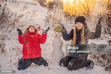 따뜻한 옷을 입은 행복한 가족 웃고 있는 어머니와 아들이 야외에서 눈사람을 만드는 모습 겨울 활동의 개념 2명에 대한 스톡 사진 및 기타 이미지 Istock