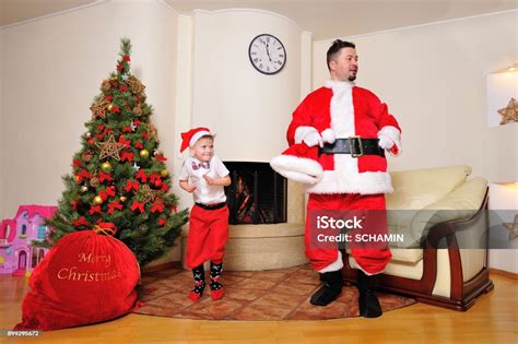 좋은 새 해 정신 크리스마스 트리 선물 가방 벽난로남자와 소년 크롤 링 재생 바보 남자 옷을 입고 산타로 아이 나비 넥타이 산타의 빨간 모자 빨간 바지 및 높은 양말 점프