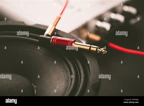 Close Up Red Auxauxiliary Cable With Male Jack With Speaker In The Background Cable For