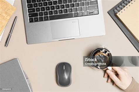 사무실 책상 테이블 여자 작업 및 물방울 커피 가방 노트북 베이지 색 배경에 노트북과 함께 손을 잡고 컵 분쇄 커피 근무 시간 최고 보기를위한 종이 가방 드립 커피 필터