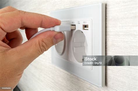 남자는 벽 충전기에 Usb 플러그를 붙든다 유럽 벽면 콘센트 또는 Ac 어댑터가 있는 소켓에 커넥터를 꽂습니다 전원 어댑터에서 Usb 케이블을 뽑습니다 휴대폰 충전기에서
