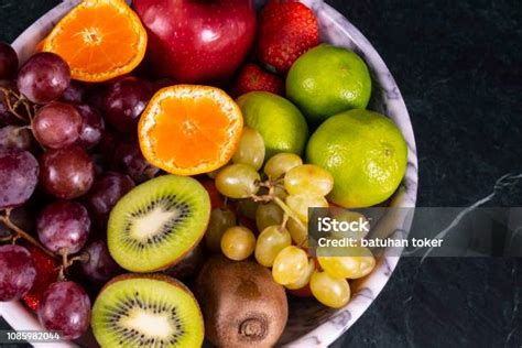 검은색 대리석에 그릇에 신선한 열 대 과일 파인애플 파파야 망고 키 위 포도 석류 석 귤 바나나 사과 수 박 조각 Pitaya