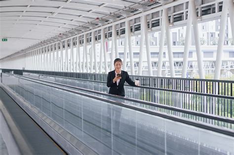 검은 양복을 입은 젊은 아시아 사업가가 전화를 사용하고 커피 한 잔을 들고 복사 공간이 있는 고가 산책로 역에 서 있습니다 30 34세에 대한 스톡 사진 및 기타 이미지