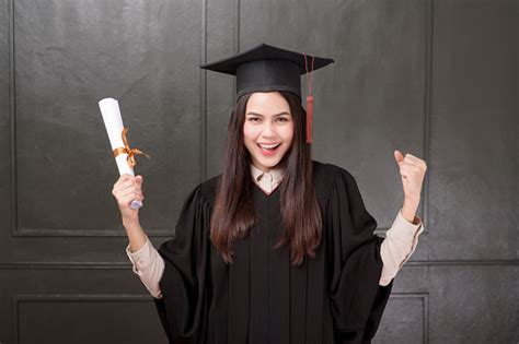 졸업 가운을 입은 젊은 여성의 초상화가 검은 배경을 미소 짓고 환호하는 모습 졸업식에 대한 스톡 사진 및 기타 이미지 졸업식