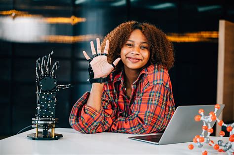 교실에서 한 흑인 십대 학생이 로봇 팔을 테스트하며 관심 있는 주제를 파헤치고 있습니다 기술 개발과 즐거운 학습을 위해 혁신과