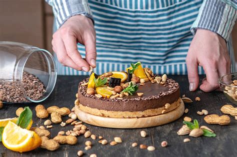 땅콩과 견과류와 초콜릿 케이크 오렌지와 민트 잎으로 장식 된 손 채식주의자를 위한 건강 한 생 디저트 과일에 대한 스톡 사진 및 기타 이미지 Istock