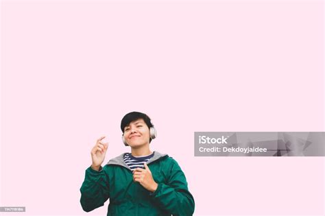 아시아 잘생긴 젊은 여자 그린 자 켓 착용 헤드셋 듣기 팝 음악과 춤 핑크 파스텔 배경에 헤드폰에서 행복 재미 Mp3 플레이어에