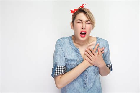 심장 마비 메이크업과 빨간 머리 띠를 가진 우연한 파란 데님 셔츠에 있는 젊은 여자의 초상화 비명을 내 고 그녀의 고통 스러운 마음을 들고 건강관리와 의술에 대한 스톡 사진