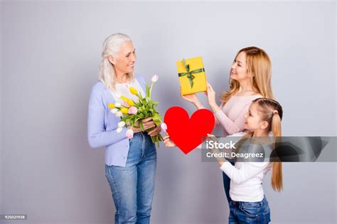 여성 케어 신뢰 양성 부드러움 사람들 3 개념입니다 예쁜 엄마 귀여운 여 학생 회색 배경에 고립 된 밝고 즐거운 흥분된 할머니에 게 현재 노란색 흰색 튤립을 주고 있다 가정