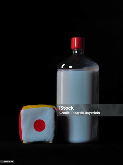 다이 는 컬러 합성 가죽으로 덮여 있으며 얼굴은 앞쪽을 향하고 검은 색 배경에 흰색 액체가 들어있는 투명한 플라스틱 병 옆에 배치됩니다 0명에 대한 스톡 사진 및 기타