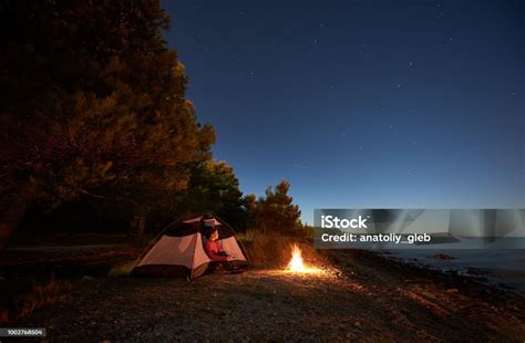 여자 별이 빛나는 하늘 아래 바다에 밤 근처 관광 텐트 캠핑 캠프 파이어에 나머지는 데 관광에 대한 스톡 사진 및 기타 이미지 관광 관광객 나무 Istock