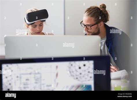 Focused Computer Programmers Programming Virtual Reality Simulator Glasses At Computer In Office