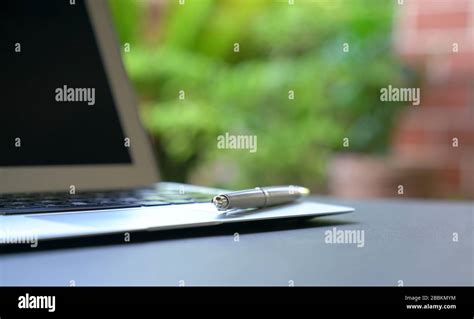 Writing Pen On Top Of Computer Laptop With Green Nature Background