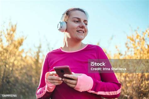 헤드폰을 사용하여 스마트 폰에서 음악을 듣고 야외에서 실행 하는 여성 주자 여성 피트니스 소녀는 외부 가을 자연 풍경을 조깅 Brand Name Smart Phone에 대한