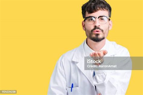 젊은 전문 과학자 남자 보고 아름 다운 되 고 공기에 손으로 키스를 날리는 카메라 격리 된 배경 위에 흰색 코트를 입고 식 사랑 감정에 대한 스톡 사진 및 기타 이미지