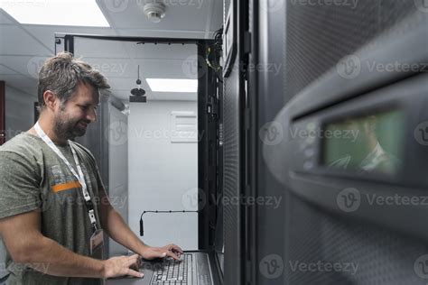 Data Center Engineer Usaing Keyboard On A Supercomputer Server Room