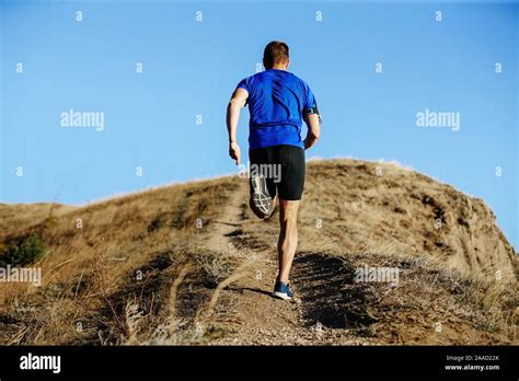 Back Male Runner Run Uphill On Mountain Trail Near The Cliff Stock Photo Alamy
