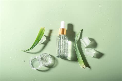 밝은 녹색 배경에 스포이드 얼음 조각 알로에 잎이 있는 투명한 화장품 병 알로에 베라 추출물 노화 방지 피부 관리 보습 및 클렌징의 개념 공간을 복사합니다 자연에 대한 스톡