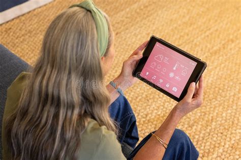Using Tablet Mature Woman Controlling Smart Home Devices In Living Room Stock Image Image Of