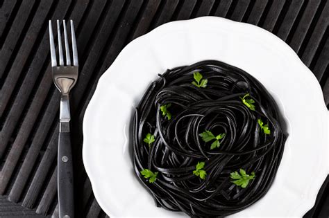 밀 싹 및 검은 오징어 잉크와 함께 파스타입니다 블랙 파스타 그리고 백색 접시에 파 슬 리입니다 포크입니다 매크로입니다 최고의 볼 수 있습니다 가로 샷입니다 공간 복사 0
